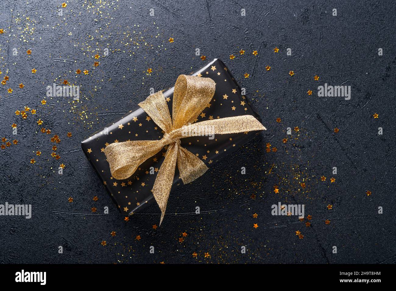 Holiday gift box or present with ribbon, golden confetti and gold ...