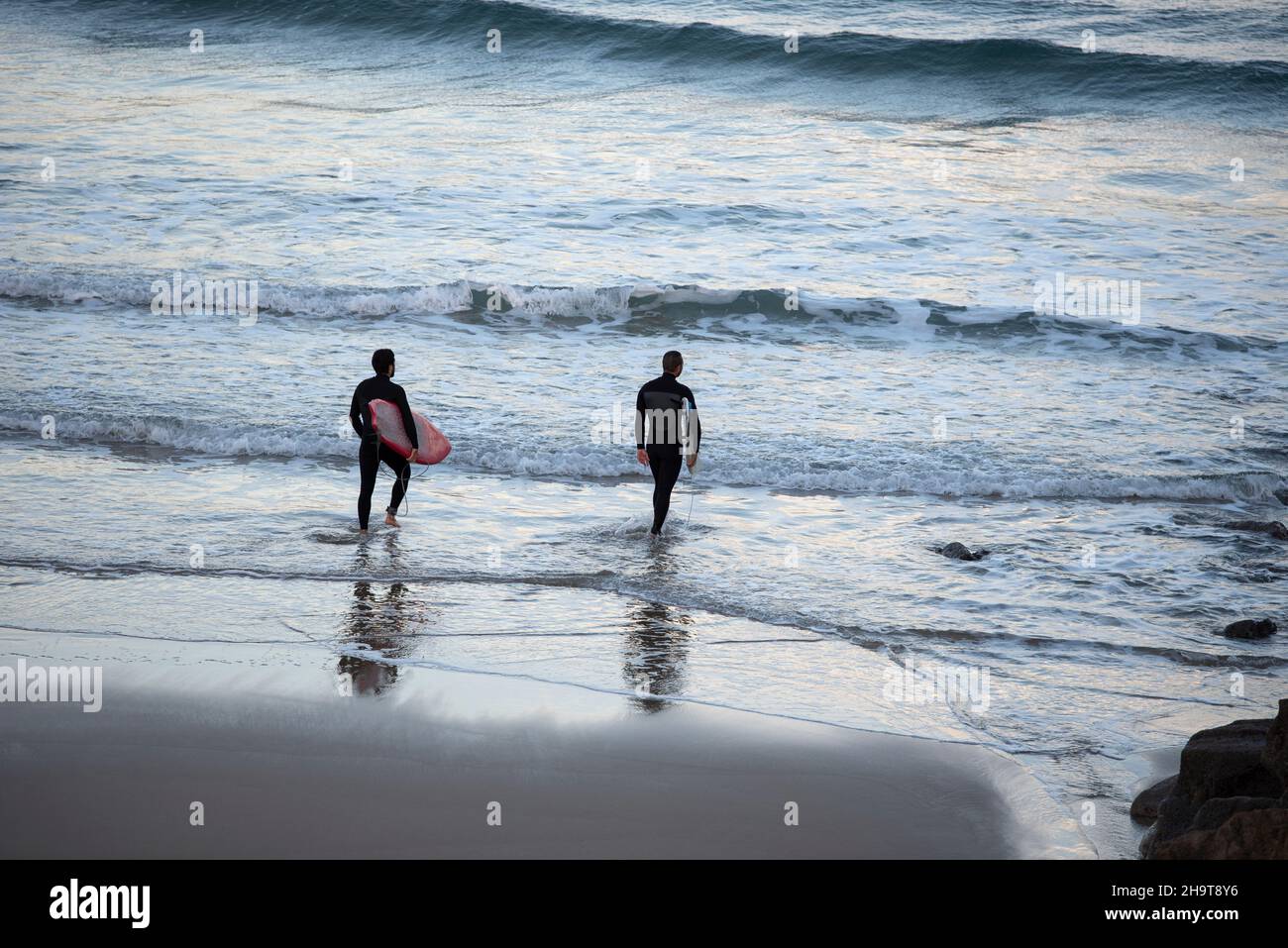 two surfers entering the water to practice surfing Stock Photo - Alamy