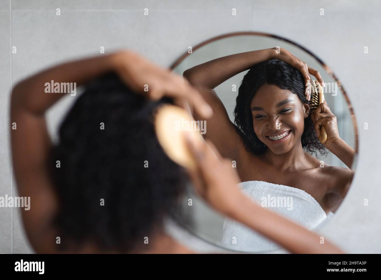 Black lady brushing hair, standing in front of mirror Stock Photo - Alamy