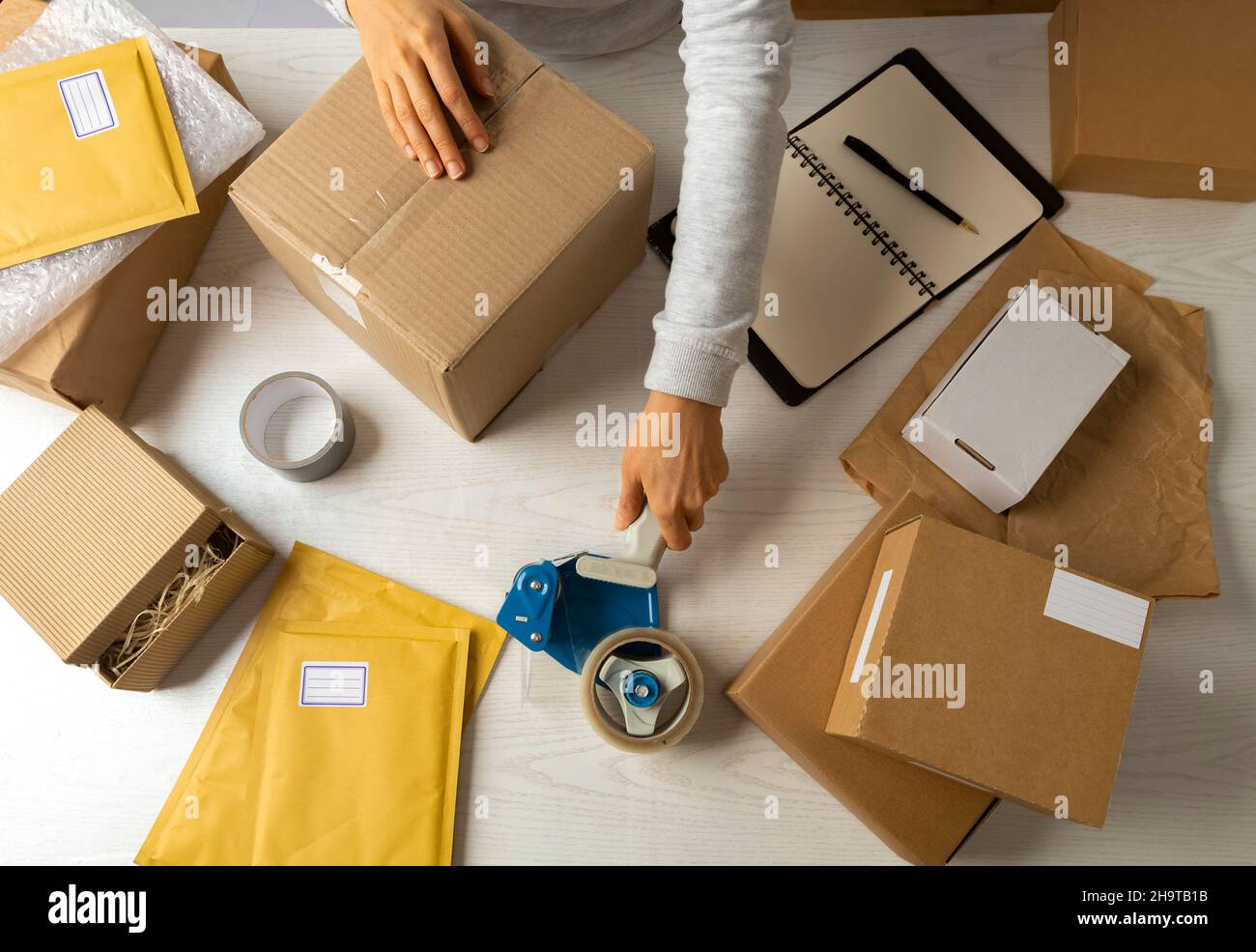 A warehouse worker packs a cardboard box with a tape dispenser Stock ...