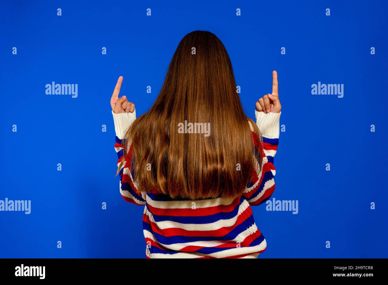 Back view of little girl pointing up at wall. Adorable girl standing ...