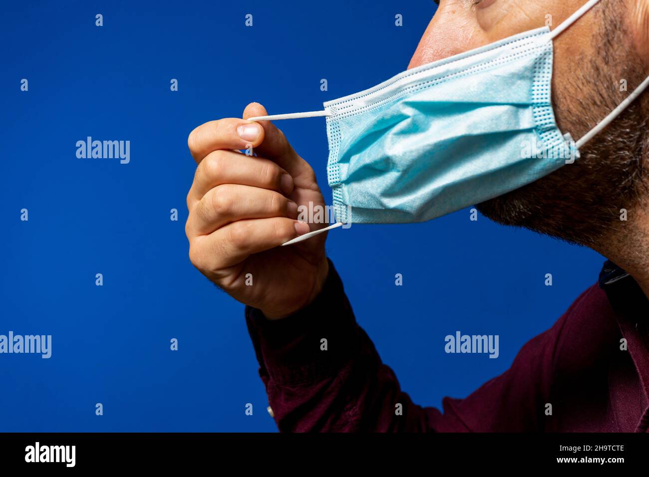 Detail of face of hispanic man taking off his surgical mask isolated on ...