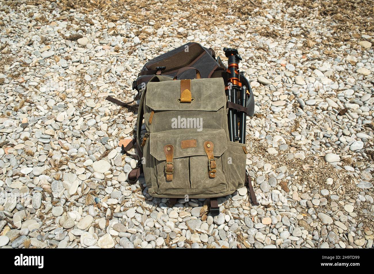 photography backpack with tripod on small stones on the beach, object ...