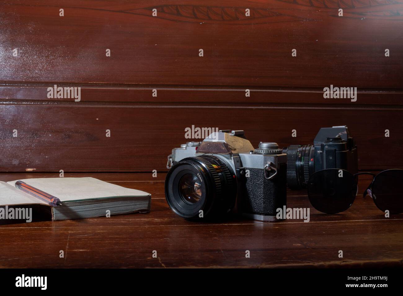 Two antique cameras next to a book and a pencil on a coffee table Stock ...