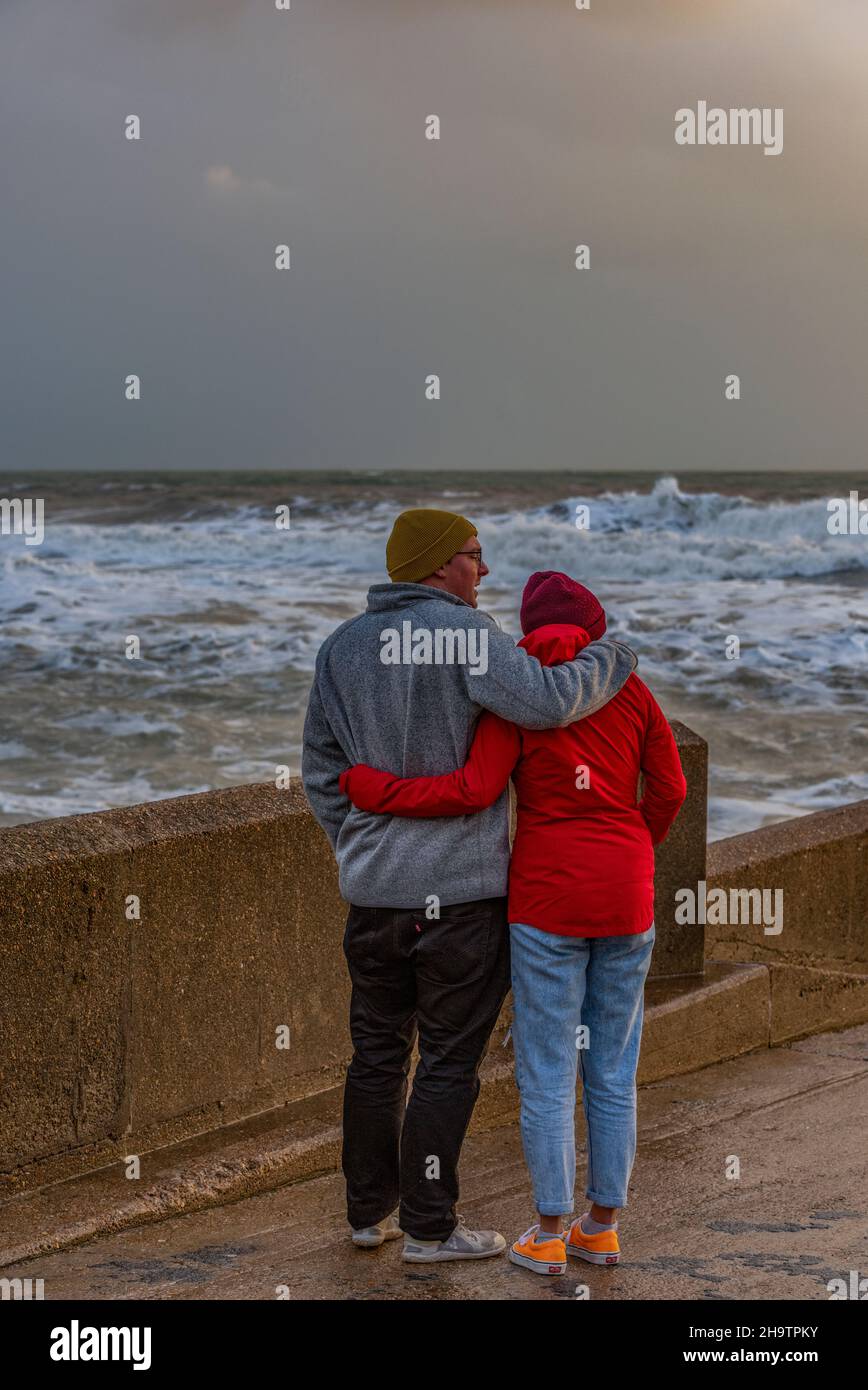 young couple cuddling watching the stormy seas at freshwater bay on the ...