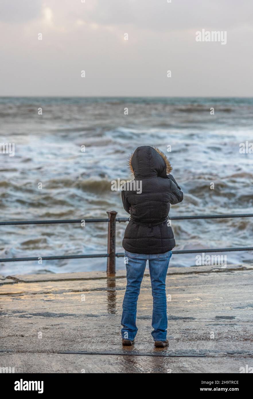 young woman in winter clothing photographing stormy weather and rough ...
