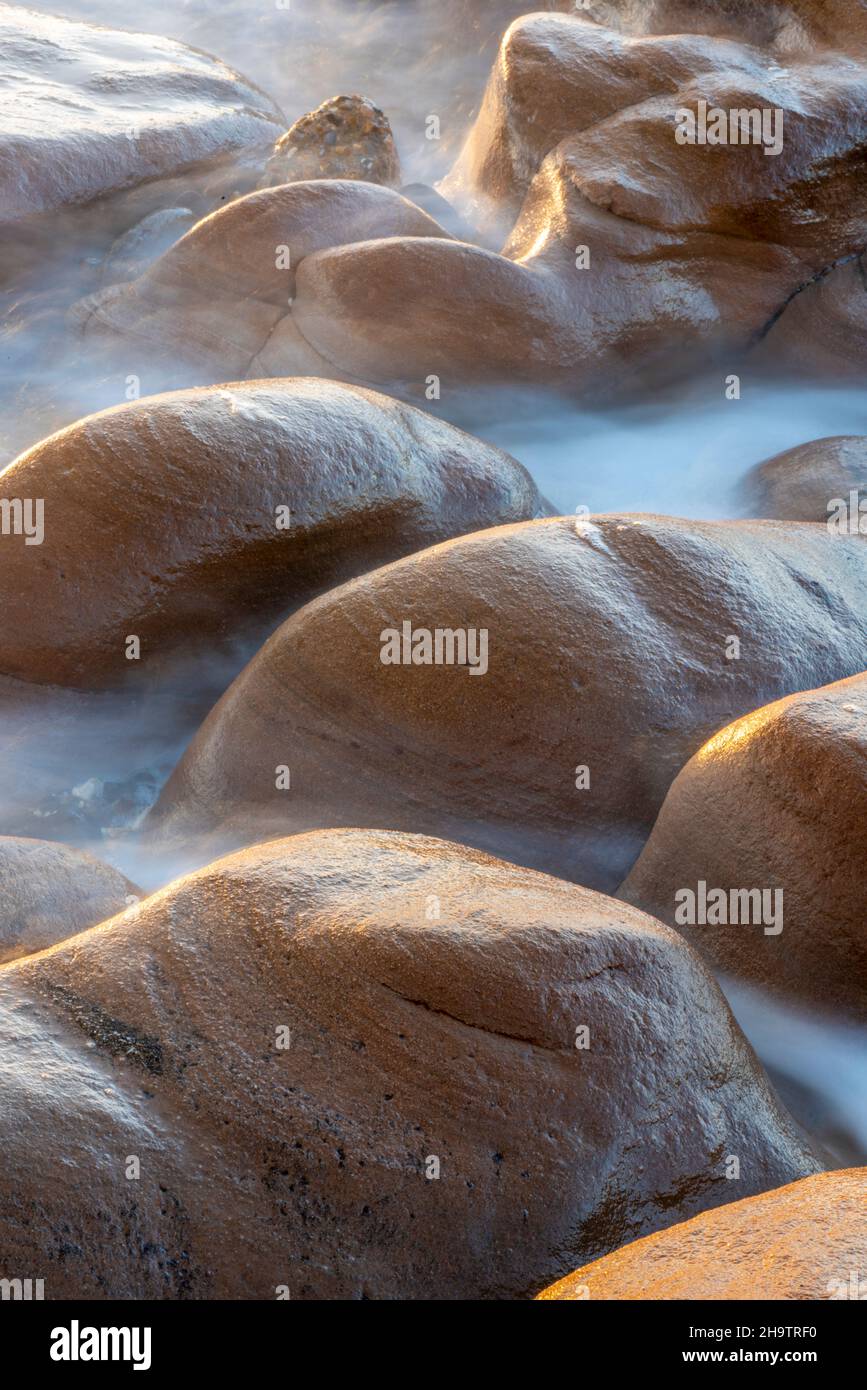 water swirling around rocks on a beach, rocks with glassy water, milky ...
