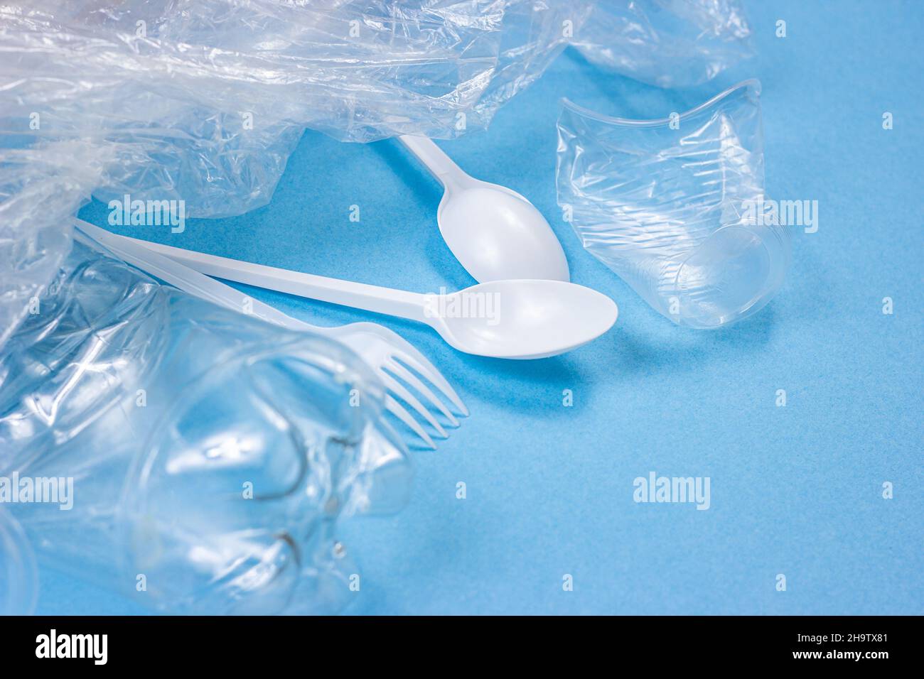 Plastic spoons, forks and cups as a disposable waste with copy space on ...
