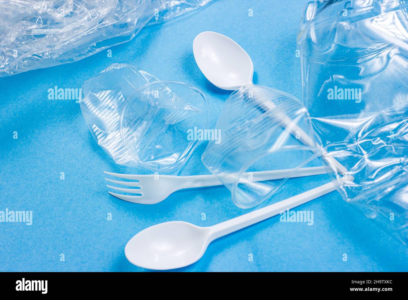 Plastic spoons, forks, bottles and cups as a disposable waste on bright ...