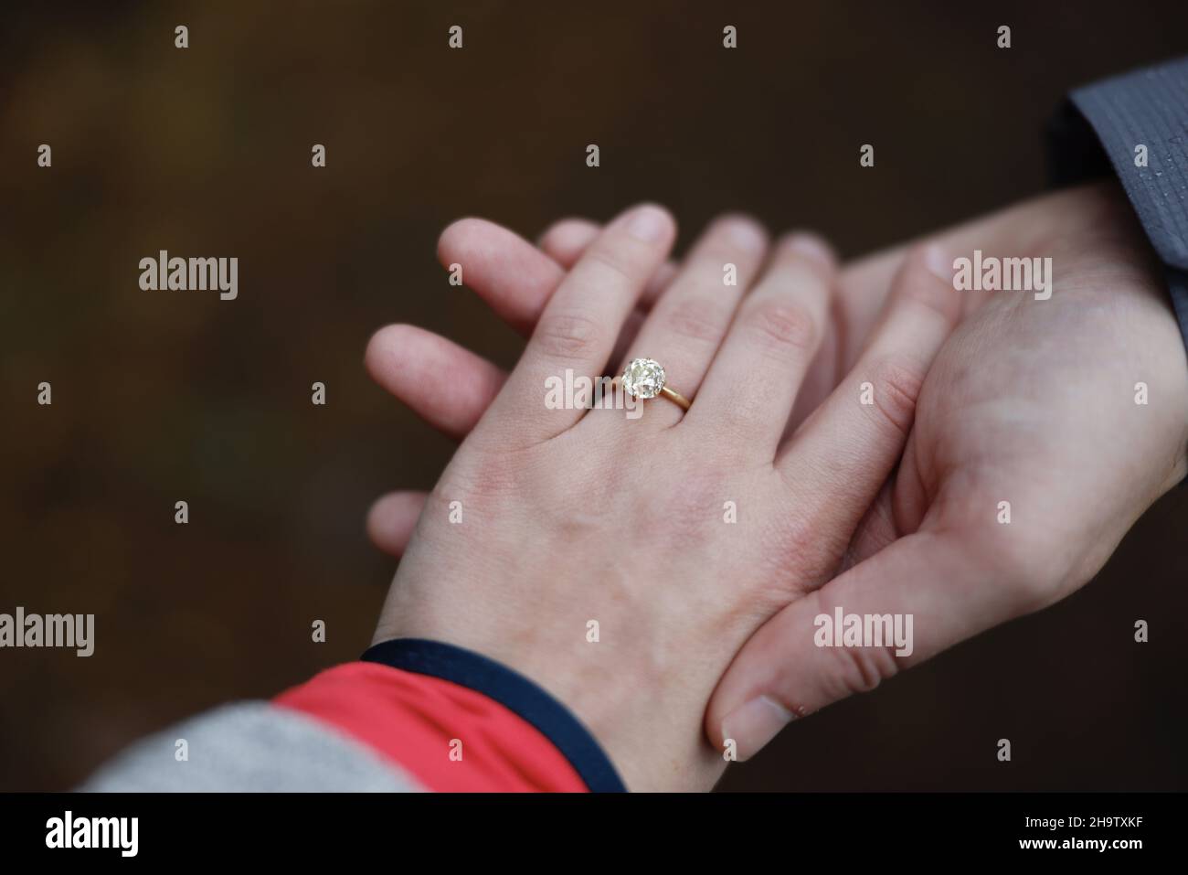 Closeup shot of a male hand holding a female hand with an engagement ...