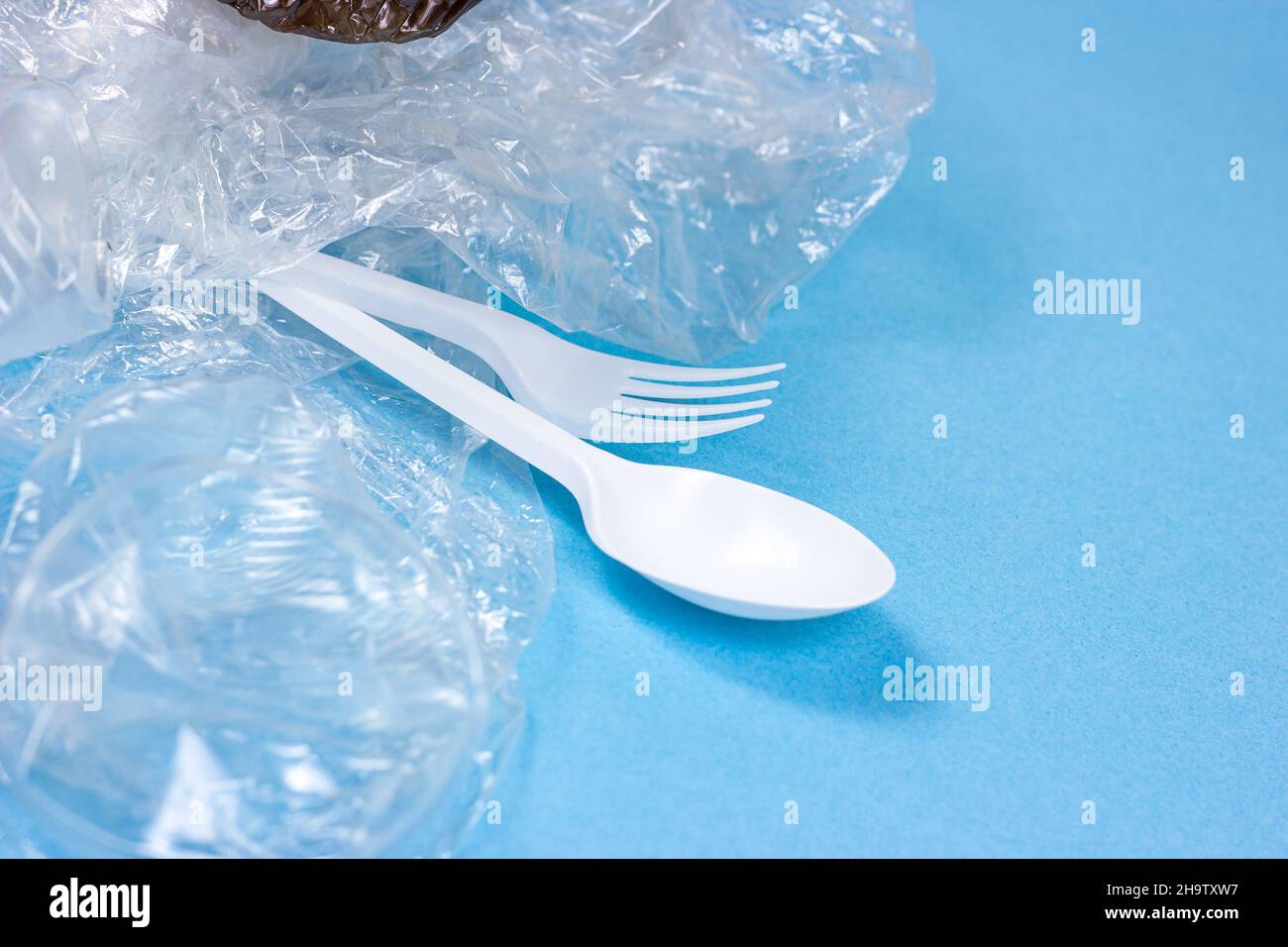 Plastic spoons, forks and cups as a disposable waste with copy space on ...