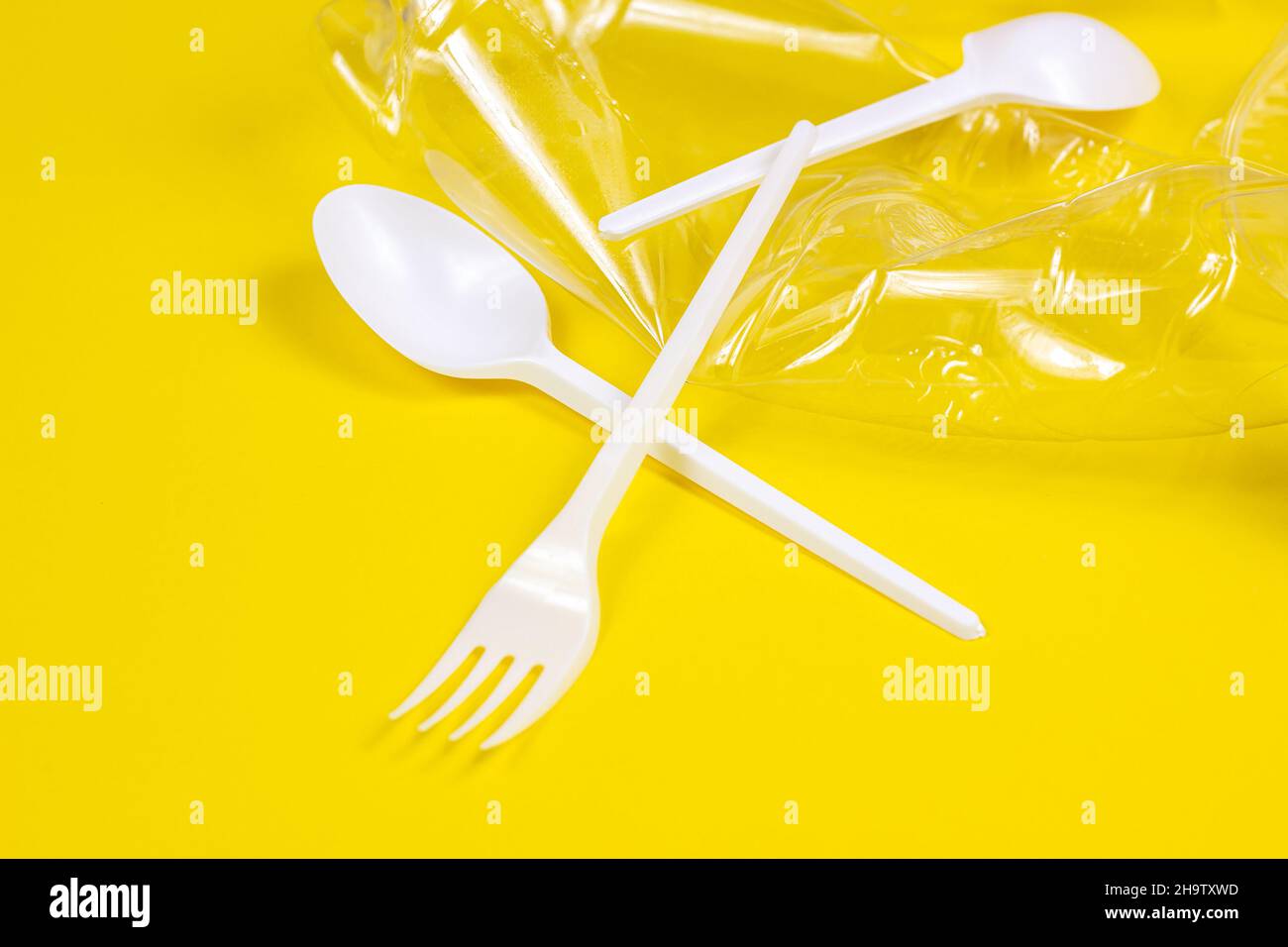 Plastic spoons, forks, bottles and cups as a disposable waste on bright ...