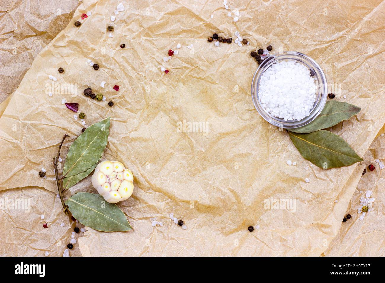Top view of white sea salt in glass bowl with spices on light beige ...