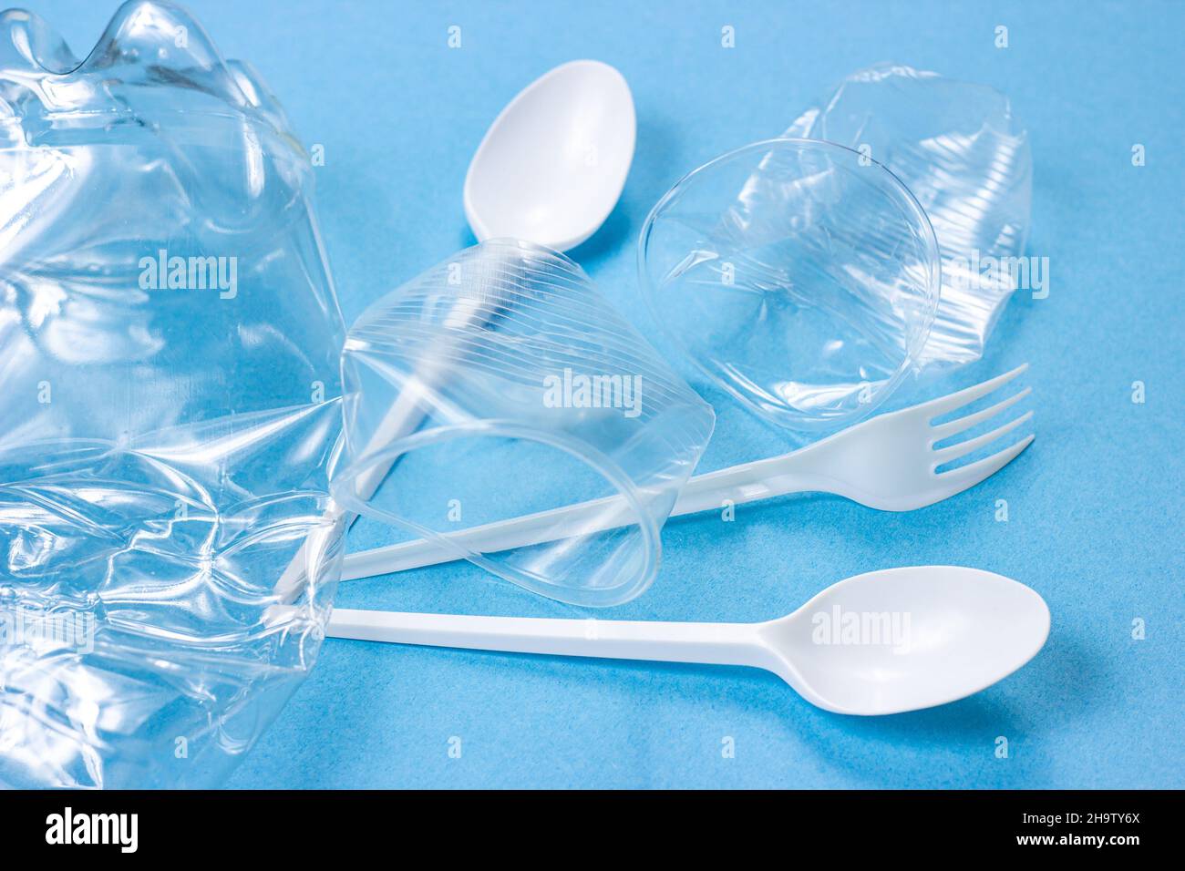 Plastic spoons, forks and cups as a disposable waste with copy space on ...