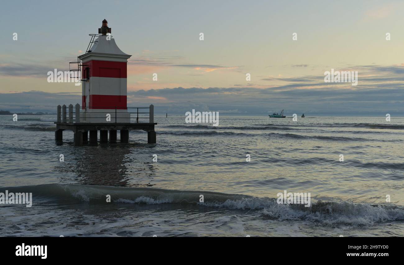 Closeup shot of the small lighthouse near the beach with beautiful sea ...