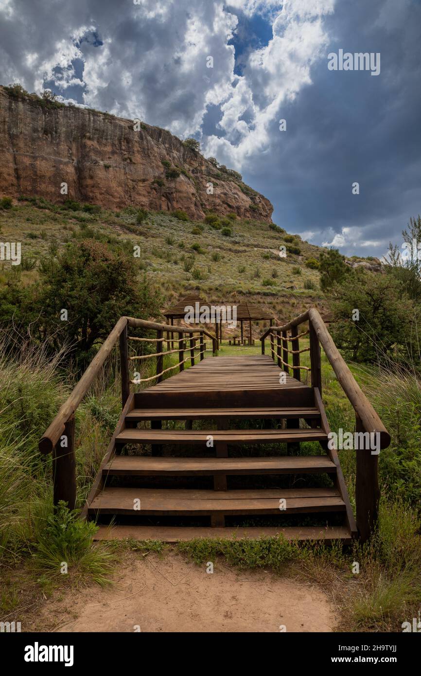 Wooden bridge leading into the distance with a mountain and dark clouds ...