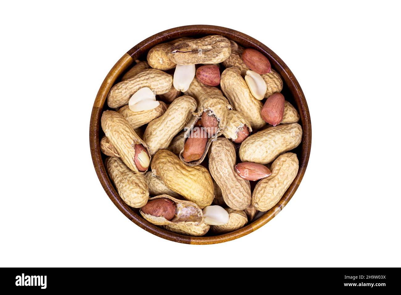 Top view of raw unpeeled peanut nuts in nutshell in brown round wooden ...