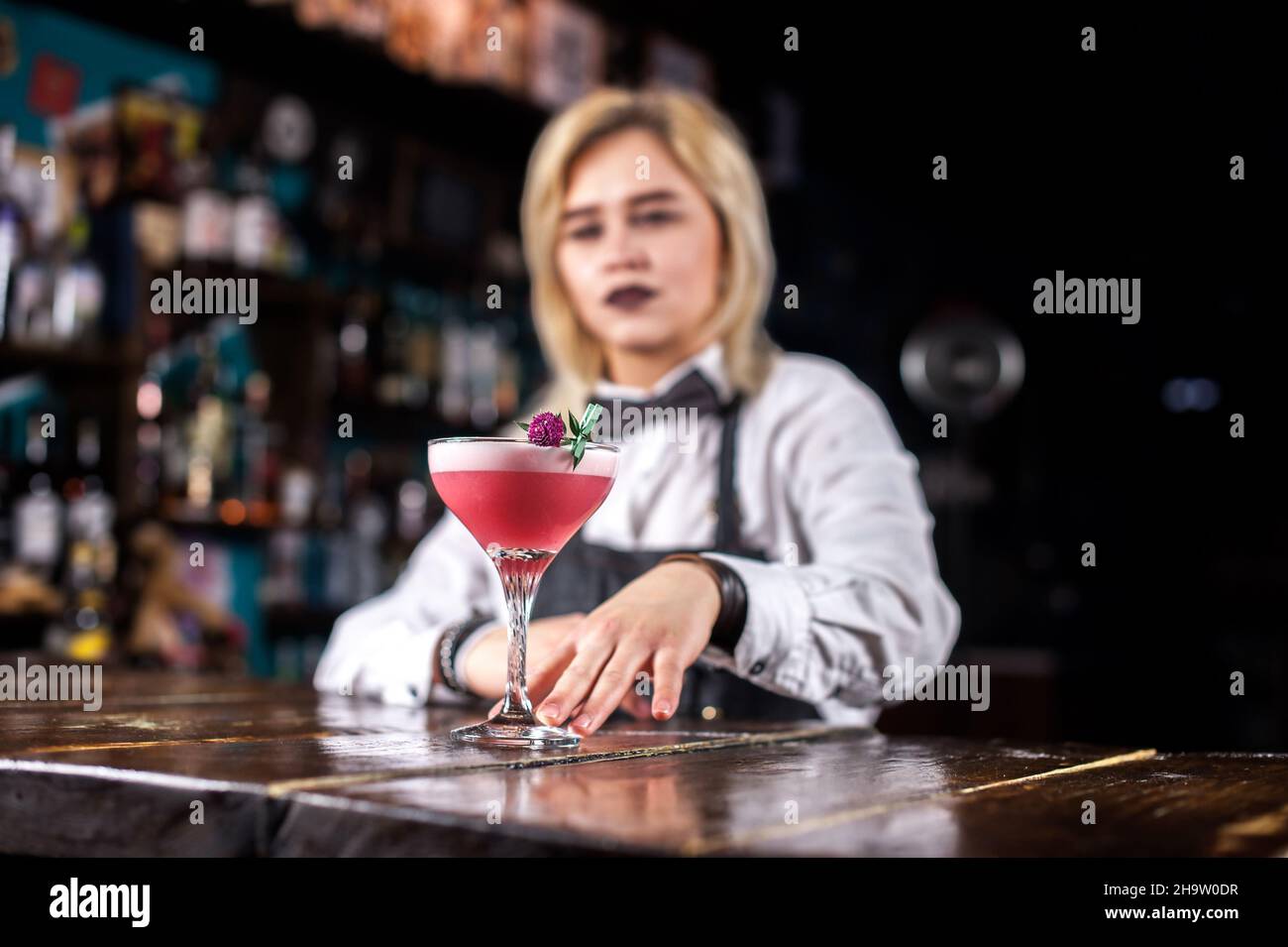 Expert woman mixologist demonstrates the process of making a cocktail ...