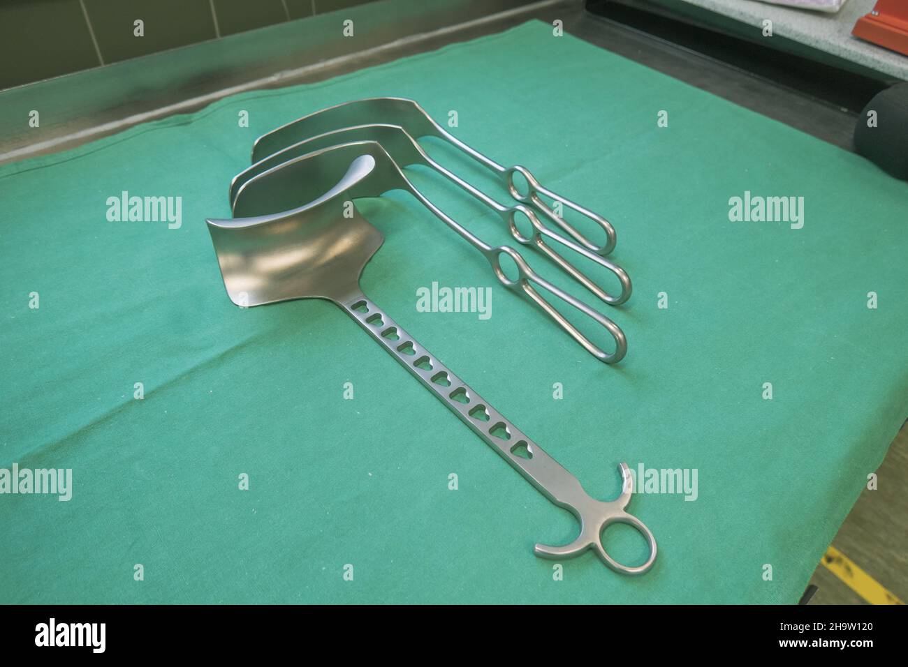 various surgical abdominal retractors lie side by side on a green base ...