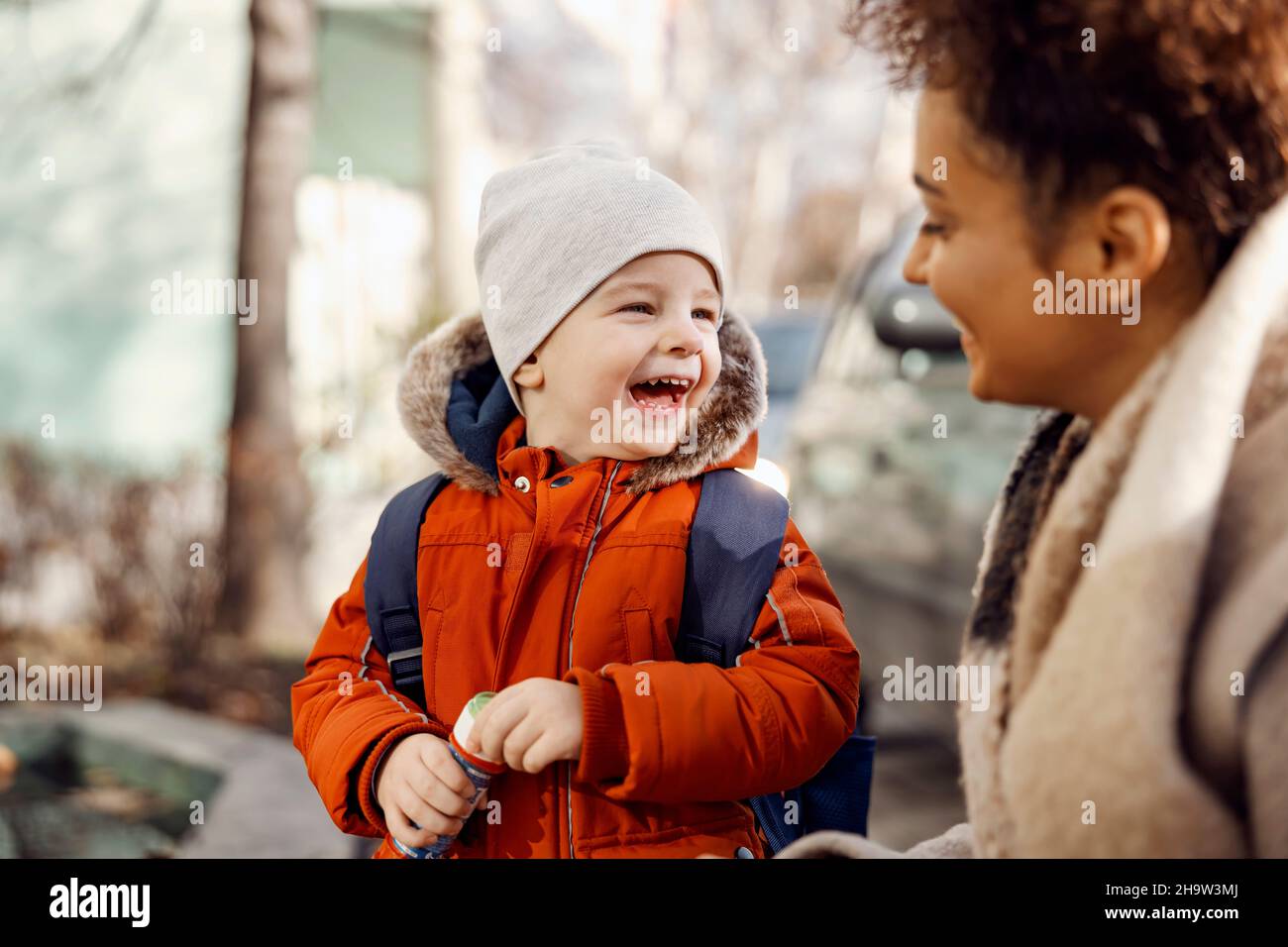 Caregiver laughing with kindergarten child in the schoolyard. Happy ...