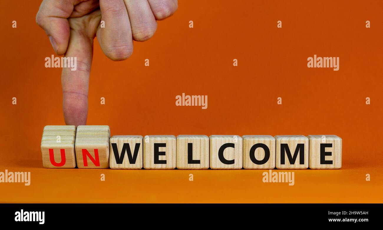 Welcome or unwelcome symbol. Businessman turns wooden cubes and changes ...