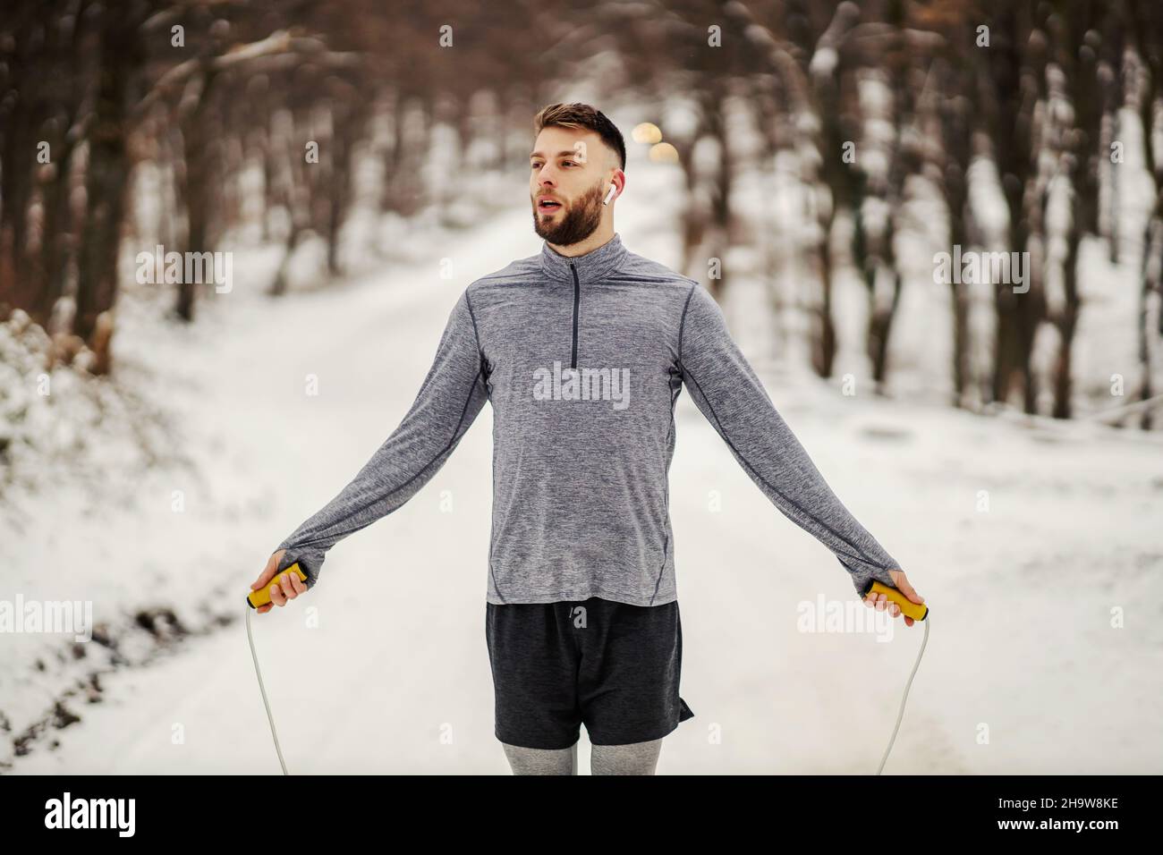 Fit sportsman jumping the rope in nature at snowy winter day. Winter ...