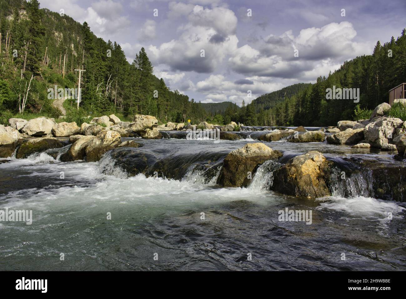 Cascade at a beautiful river lined with alpine trees Stock Photo - Alamy