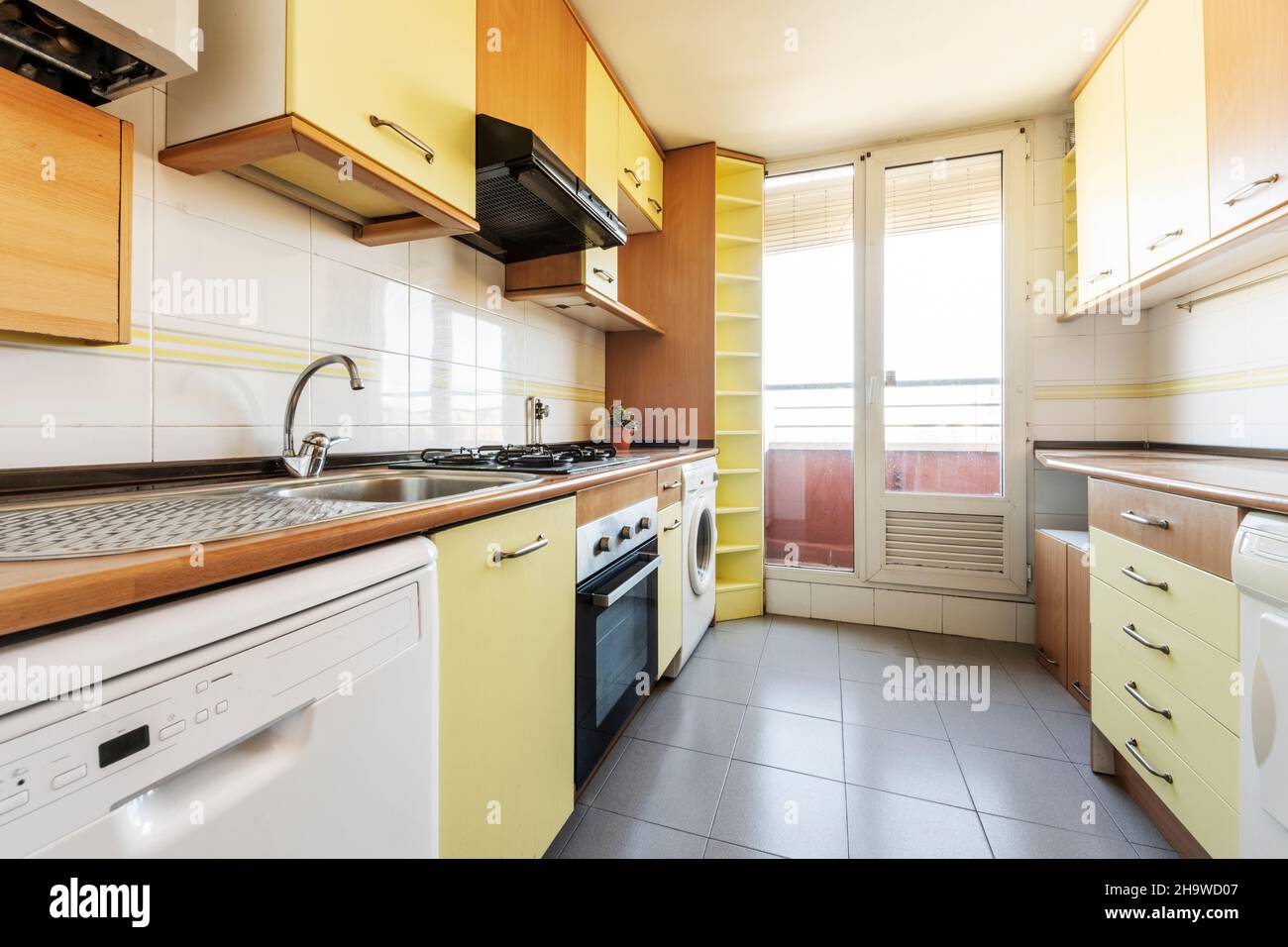 Conventional kitchen with yellow and cherry wood cabinets with black ...