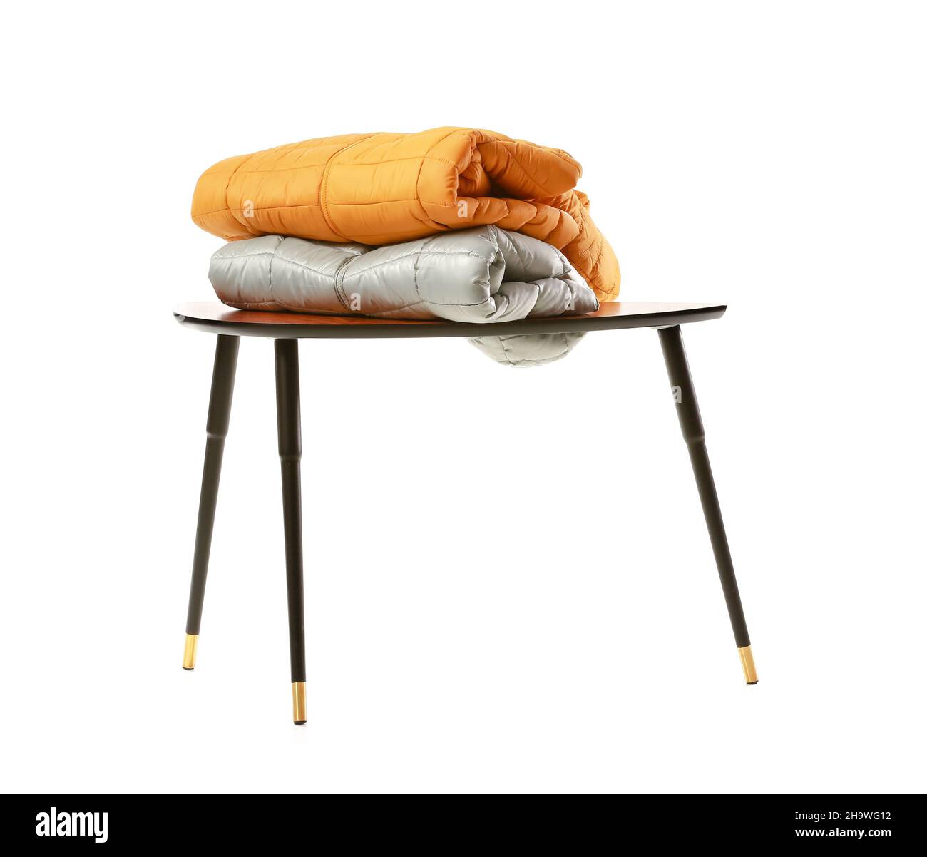 Folded down jackets on table against white background Stock Photo - Alamy