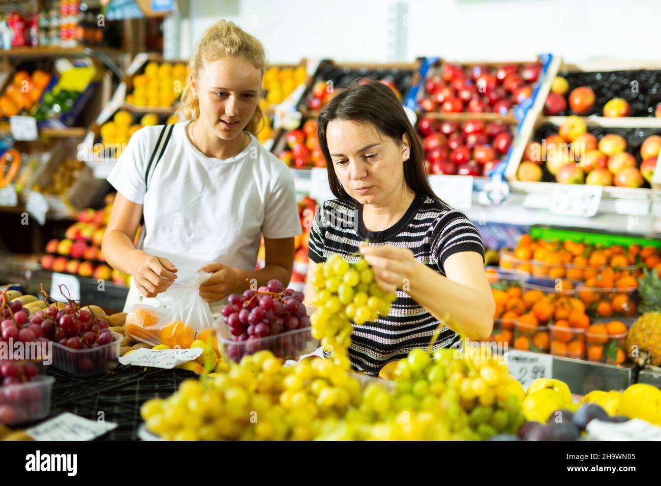 Teenage girl and her mother buying grape at grocery Stock Photo - Alamy