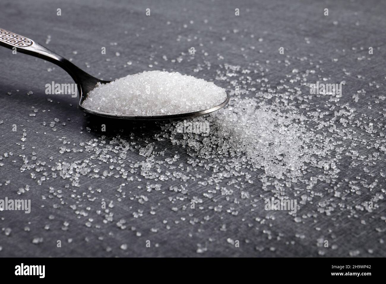 Teaspoon with white sugar. Black chalk board background Stock Photo - Alamy