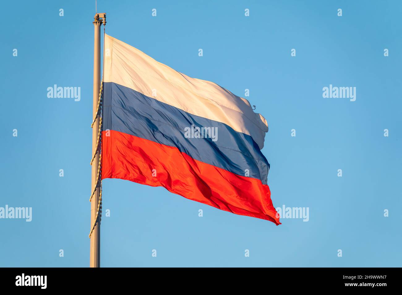 Russian tricolor flag waving in the wind against a blue sky. Russian ...