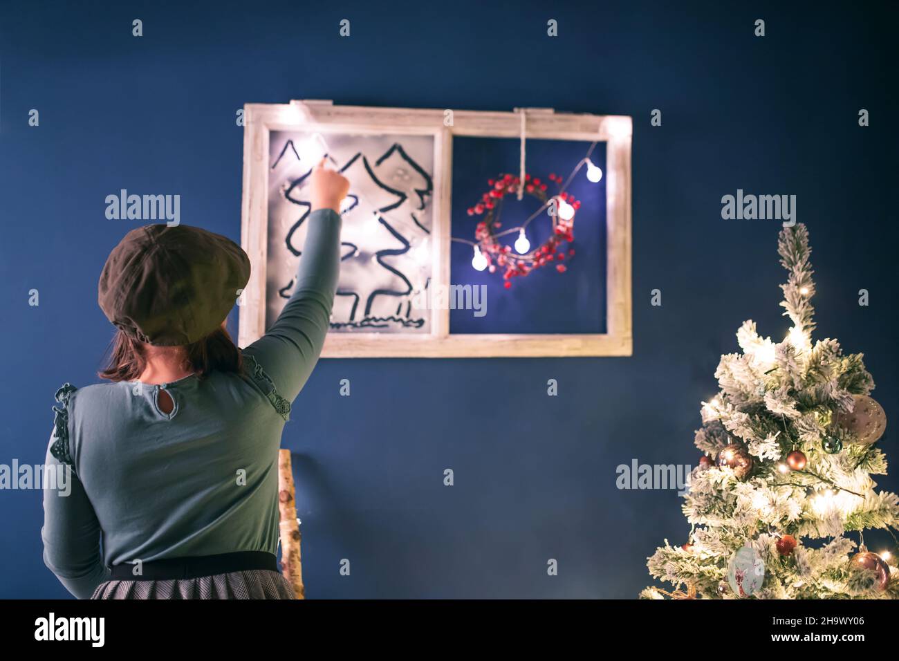 Cute little girl writing on snowy window, Christmas decorations and ...