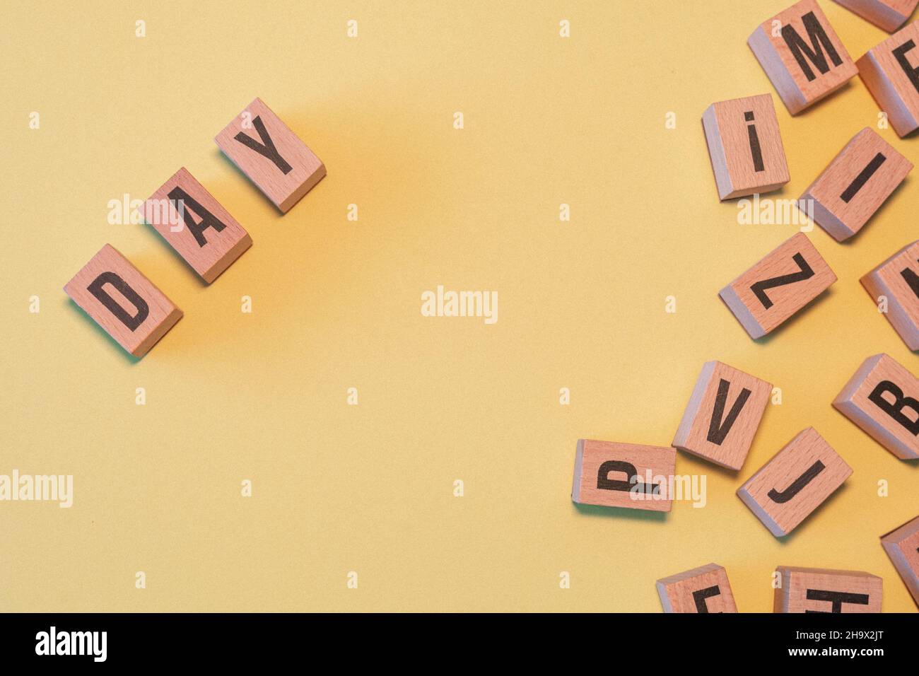 Word DAY taken from a pile of wooden letter blocks in the yellow ...
