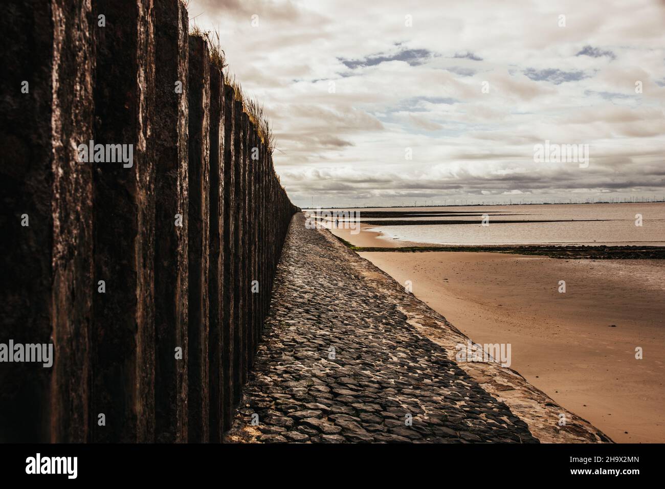 Long stone wall and a stone narrow path built in front of a sandy beach ...