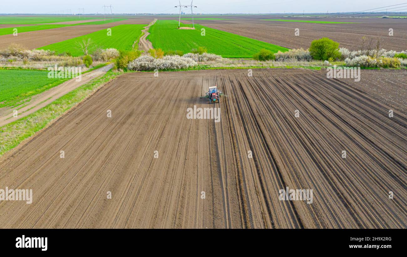 Above view, of tractor as pulling mechanical seeder machine over arable ...