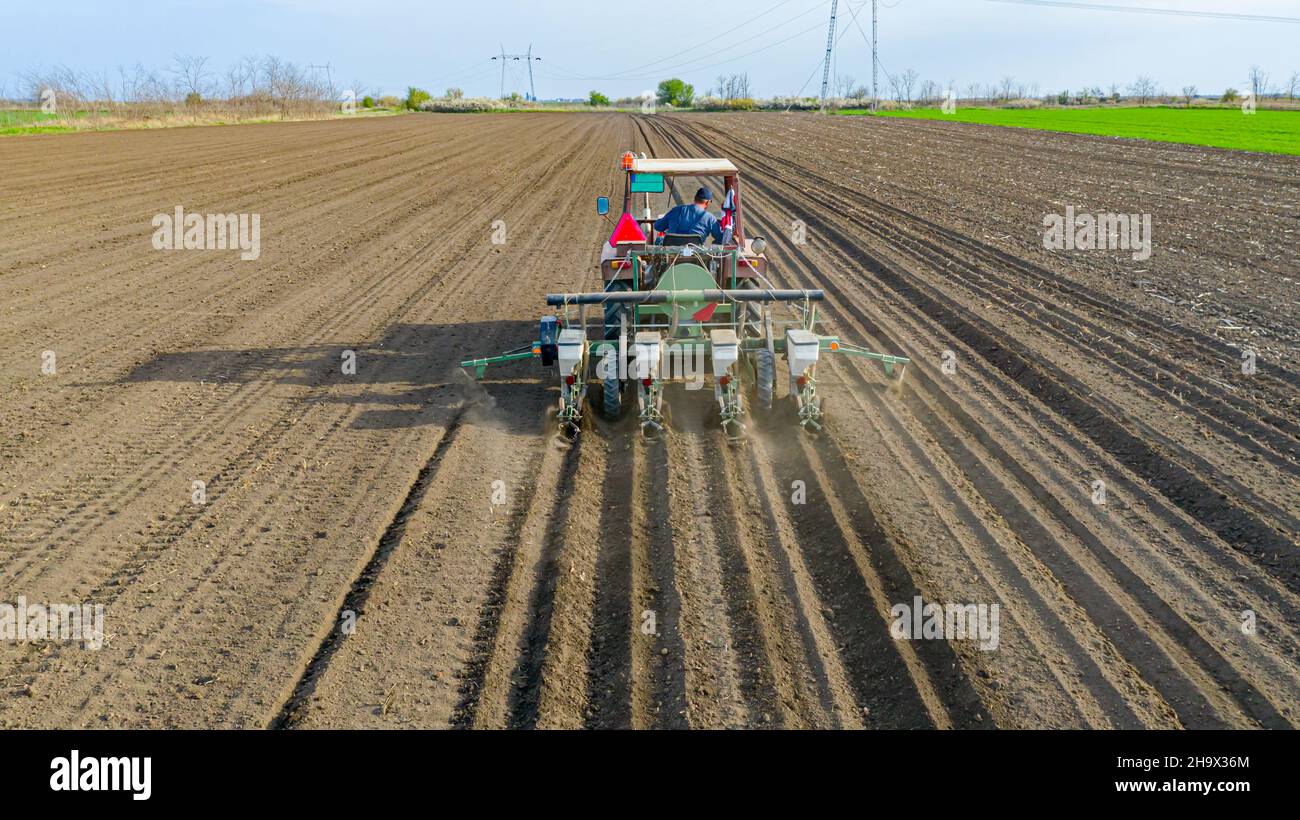 Above view, of tractor as pulling mechanical seeder machine over arable ...