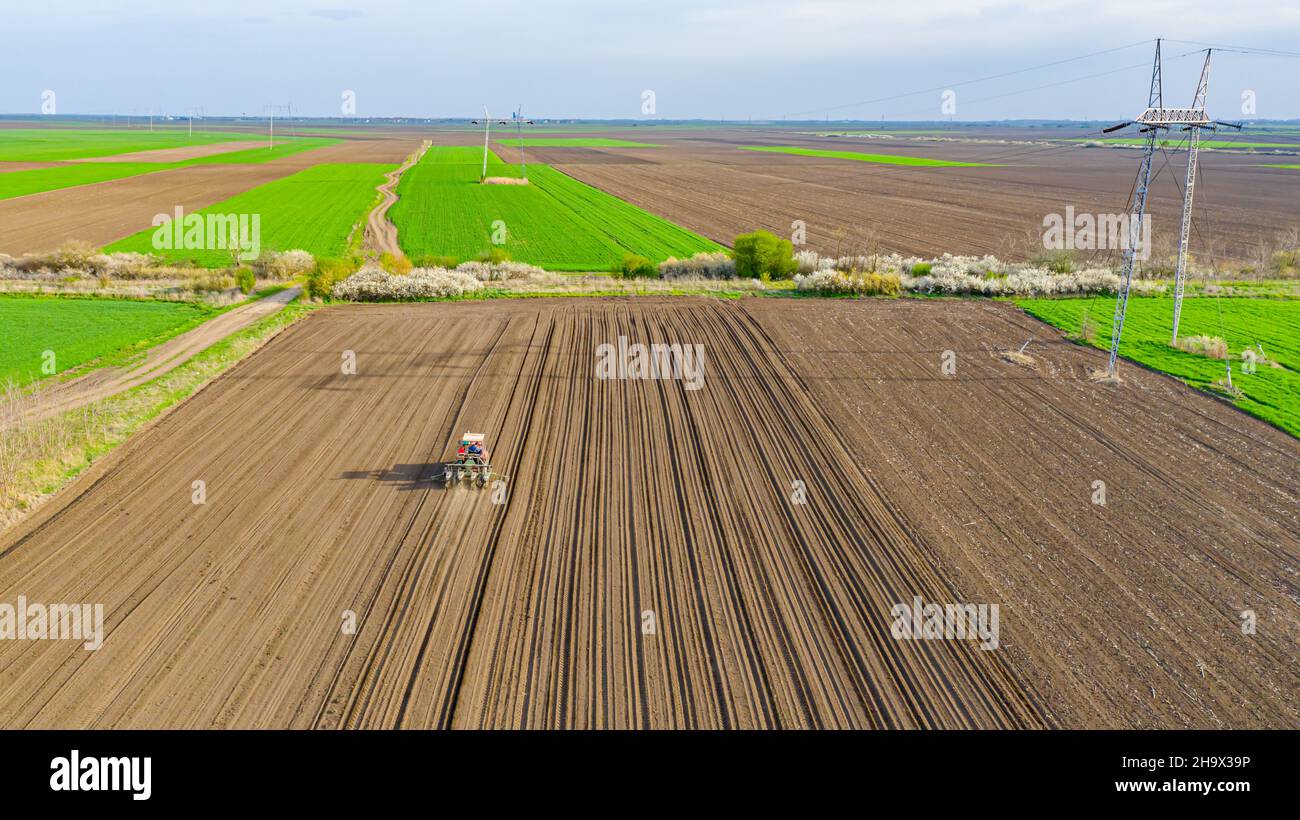 Above view, of tractor as pulling mechanical seeder machine over arable ...