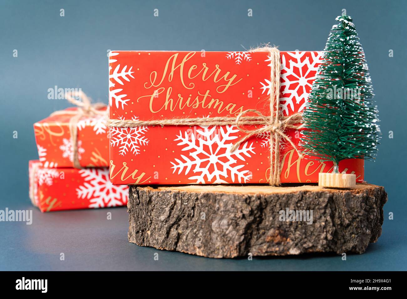 Christmas gifts in a red wrapper on a cut of a tree with a small ...
