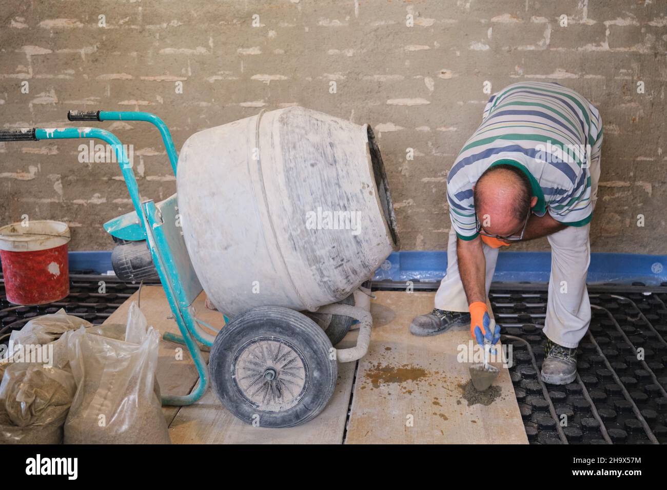 Construction worker checking the quality of the concrete into the mixer ...