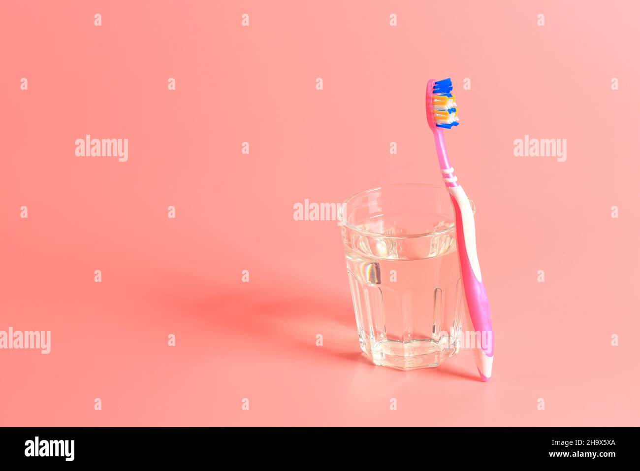 toothbrush and a glass of water on a pink background Stock Photo - Alamy
