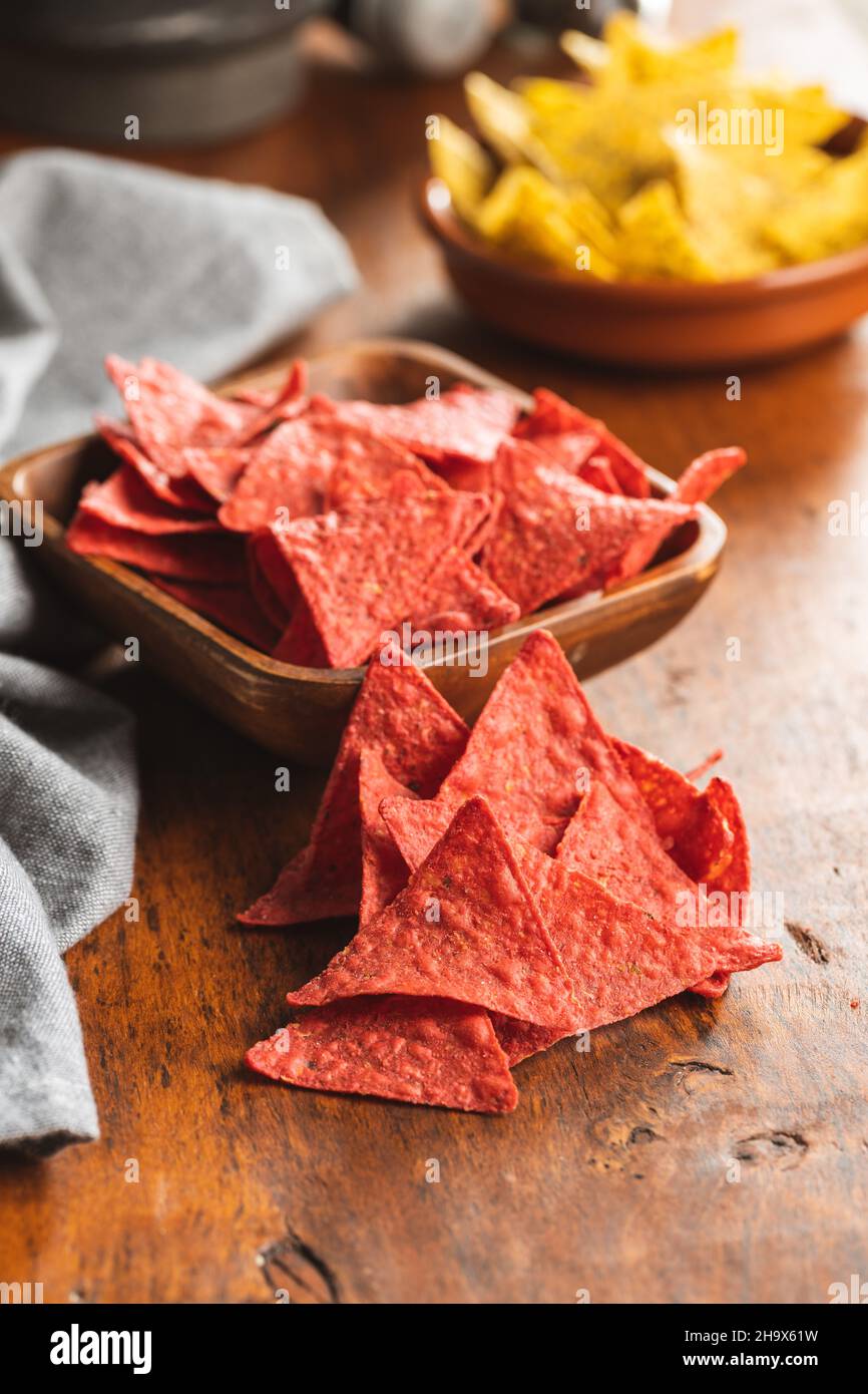 Salted tortilla chips triangle with red beet flavor on wooden table ...