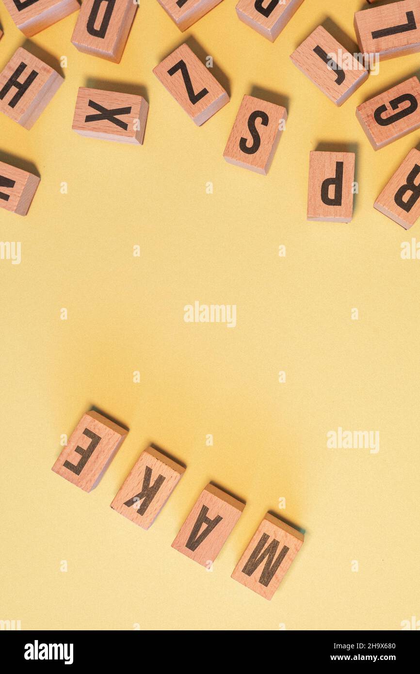 Word MAKE, taken from a pile of wooden letter blocks in the vertical ...