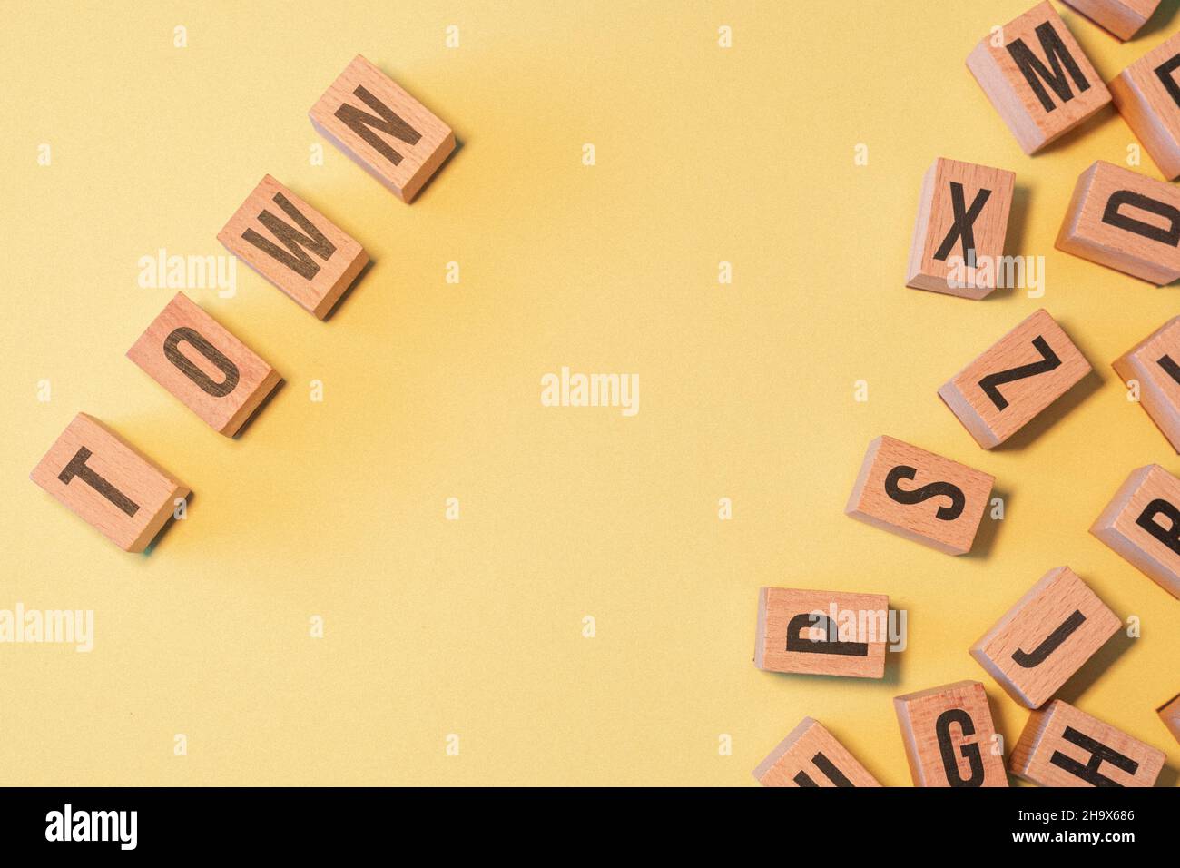 Word TOWN, taken from a pile of wooden letter blocks with yellow ...