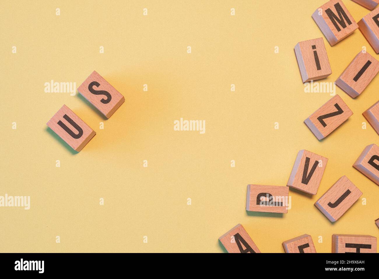Word US taken from a pile of wooden letter blocks with yellow ...