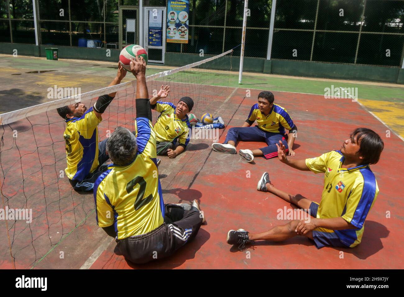athletes with disabilities practice sitting volleyball on the indoor ...