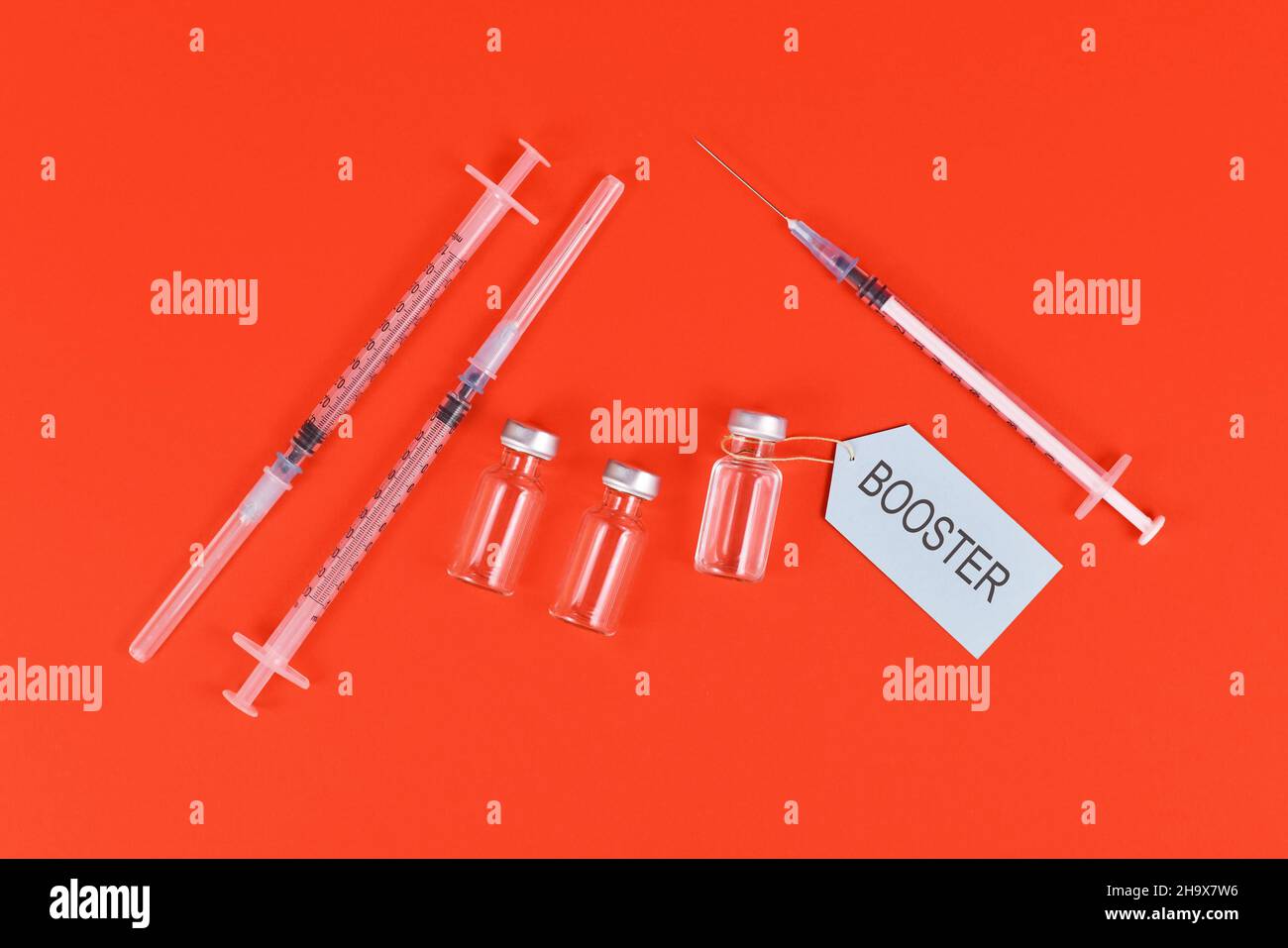Corina virus booster vaccination concept with vials and syringes on red ...
