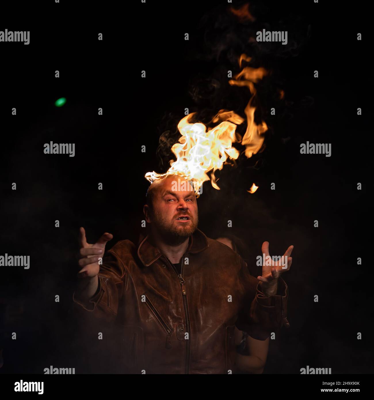 Bald man in a leather jacket with a burning head on a dark background ...