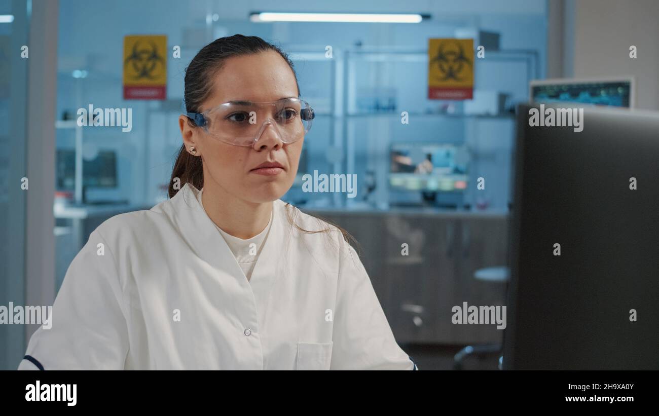Woman chemist working on computer in science laboratory, using ...