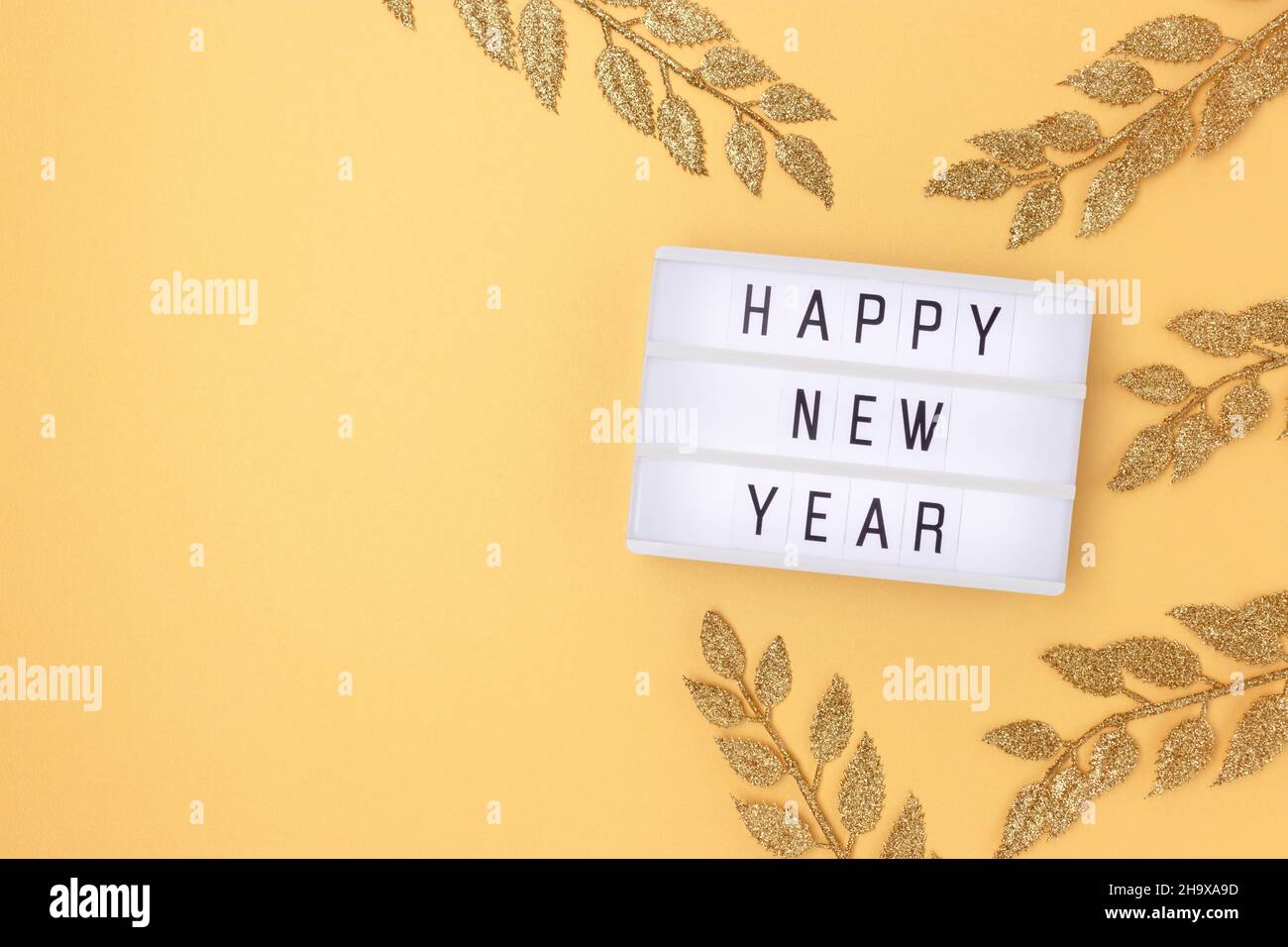 Happy New Year. Lightbox and glittering branches on a golden background ...